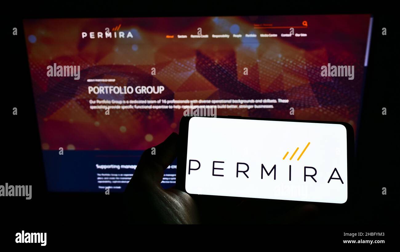 Person holding mobile phone with logo of British investment company ...