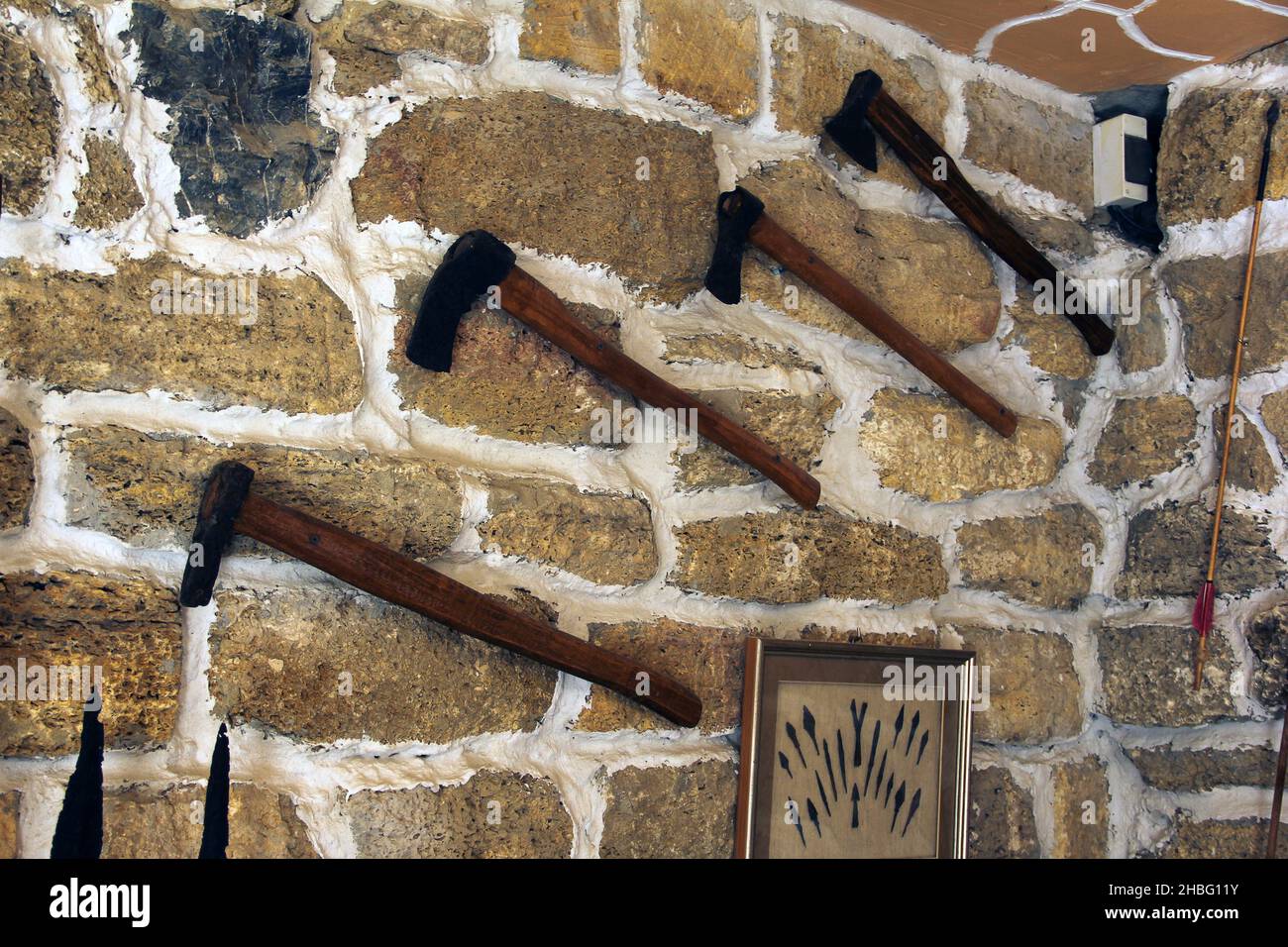 A set of old axes hang on the wall. Collection of axes. Old weapon ...