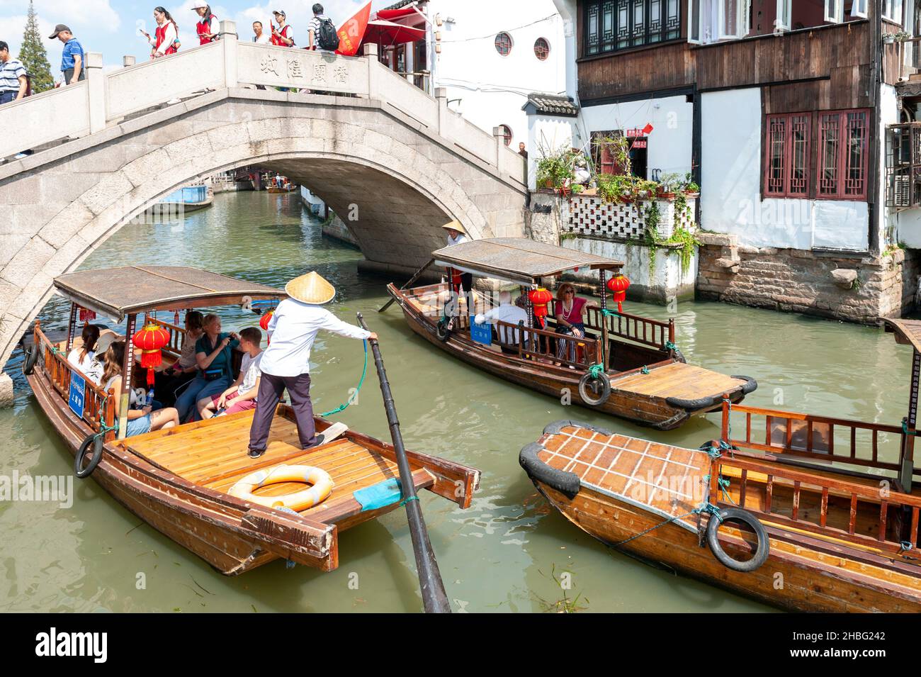 Tourist wooden rowboat cruising pass an old stone bridge lies over a ...
