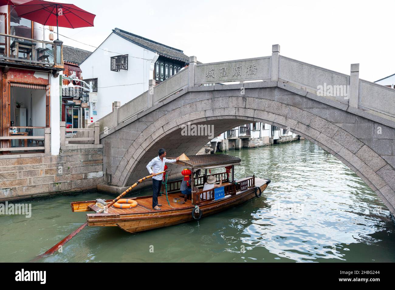 Tourist wooden rowboat cruising pass an old stone bridge lies over a ...