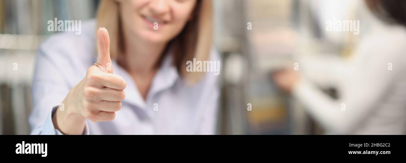 Woman seller showing thumb up forward with samples of fabrics in store ...