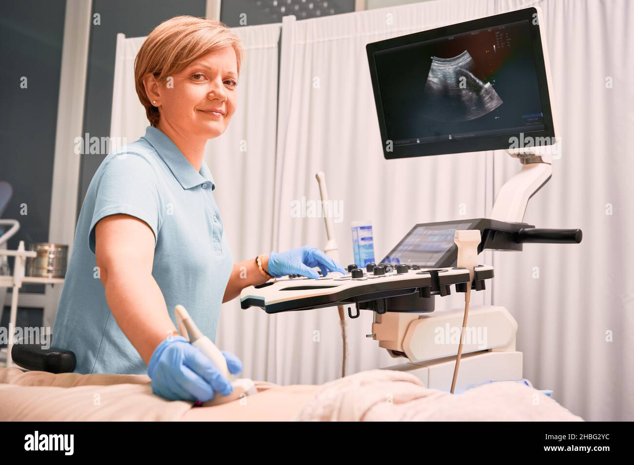Female sonographer examining patient with ultrasound scanner. Doctor ...