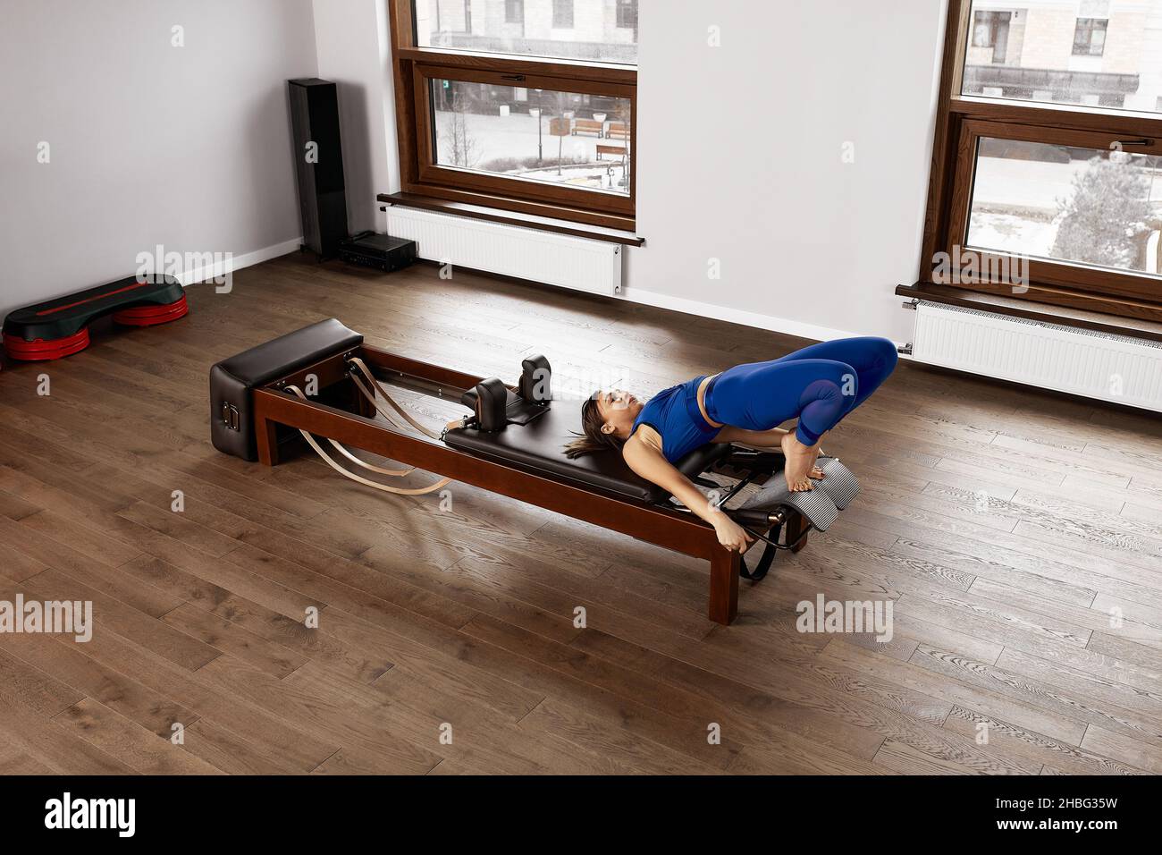 The instructor does exercises on the reformer, a beautiful girl trains ...