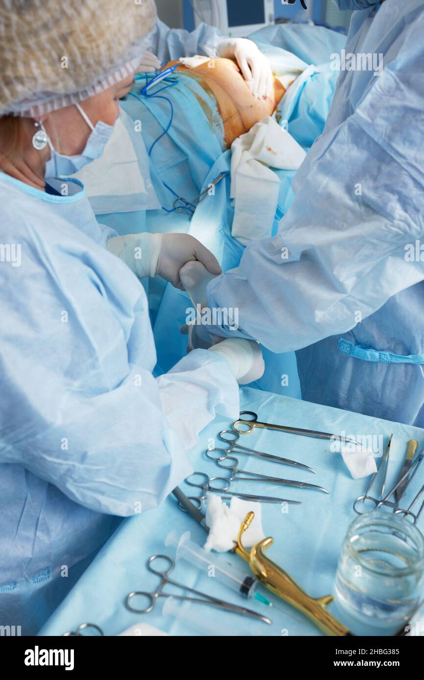 Surgeon and the nurse are preparing for surgery in the operating room ...
