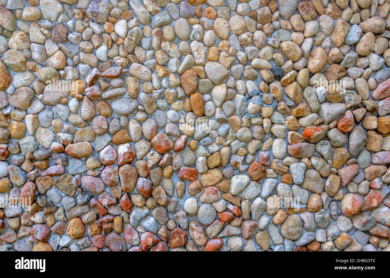 Rounded pebbles held with concrete in a wall for use as a background ...