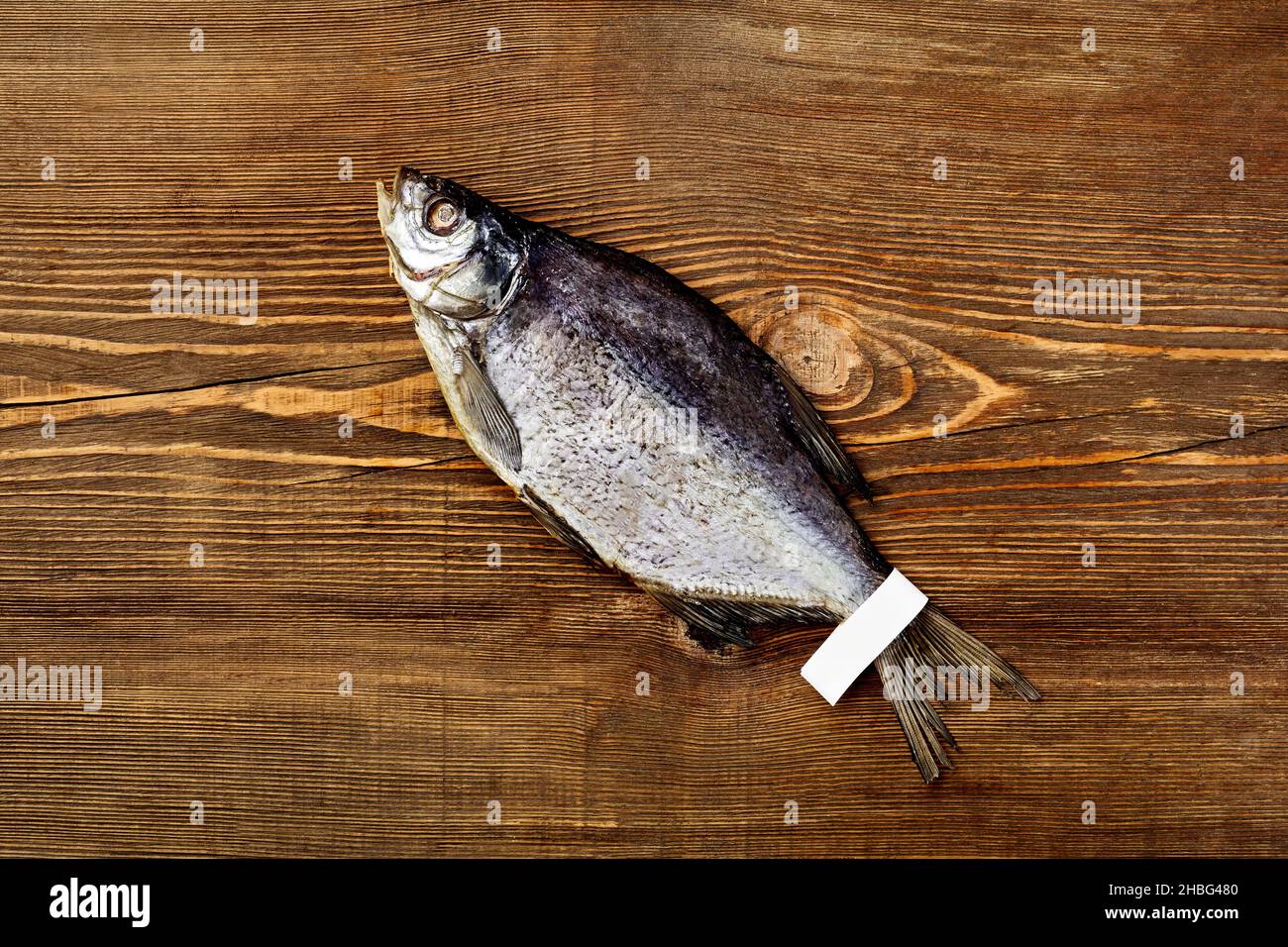 Top view of salted jerked roach fish with label on tail on wooden ...