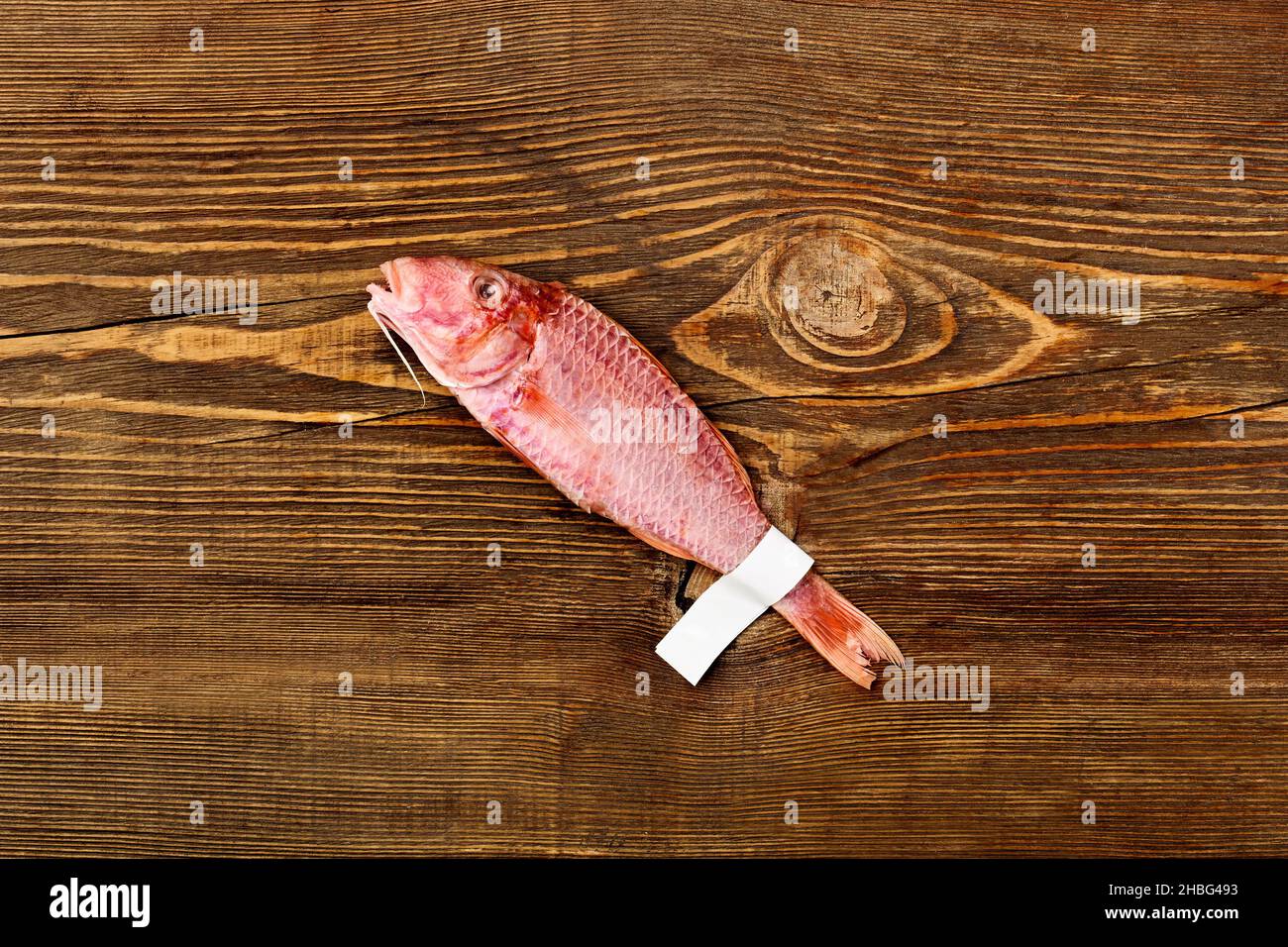 Salted sun-dried red mullet with label on tail on wooden table Stock ...