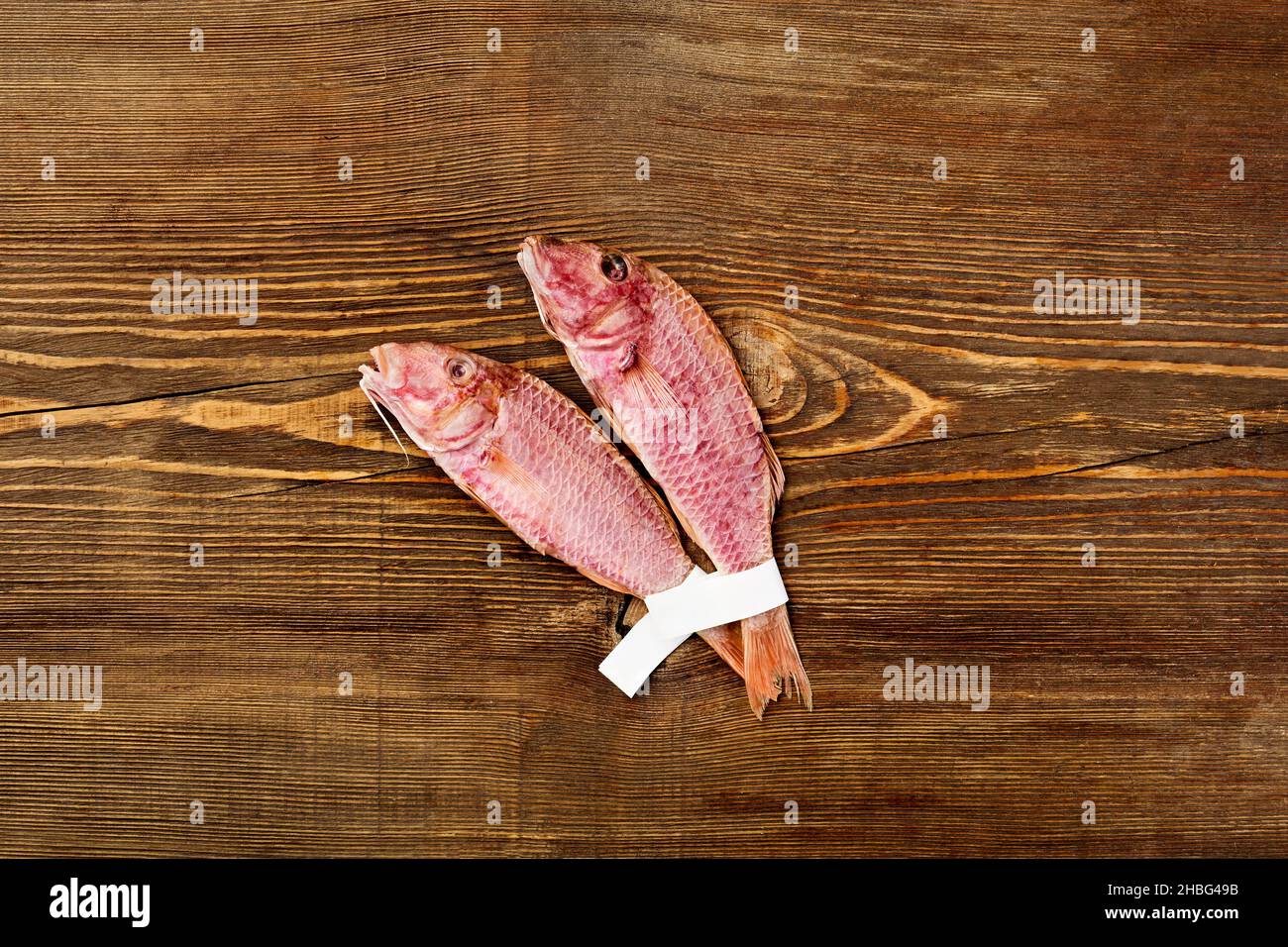 Two salted air-dried surmullets with labels on tails on wooden ...