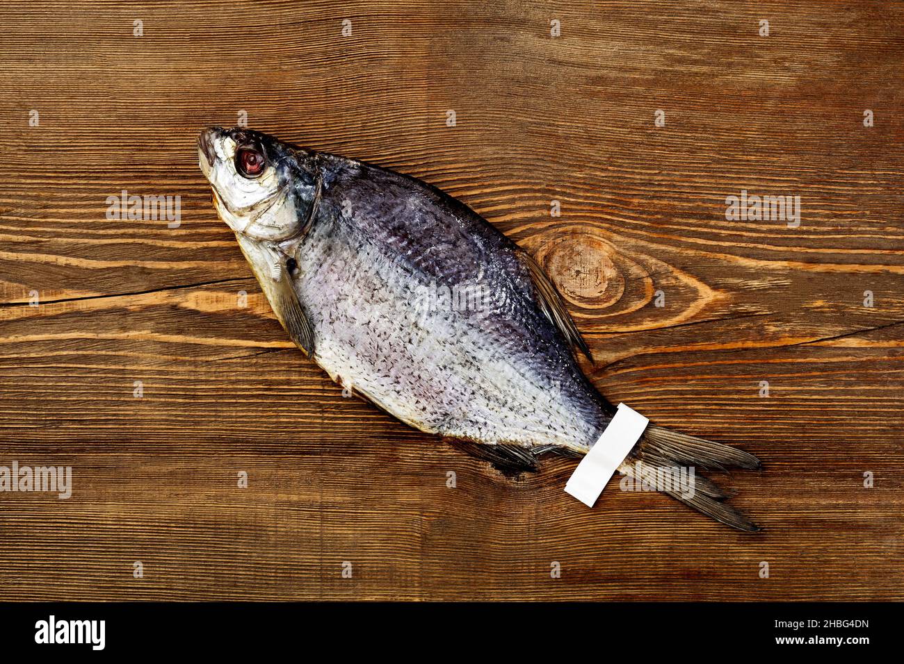 One whole salted sun-dried bream with label on tail on wooden ...
