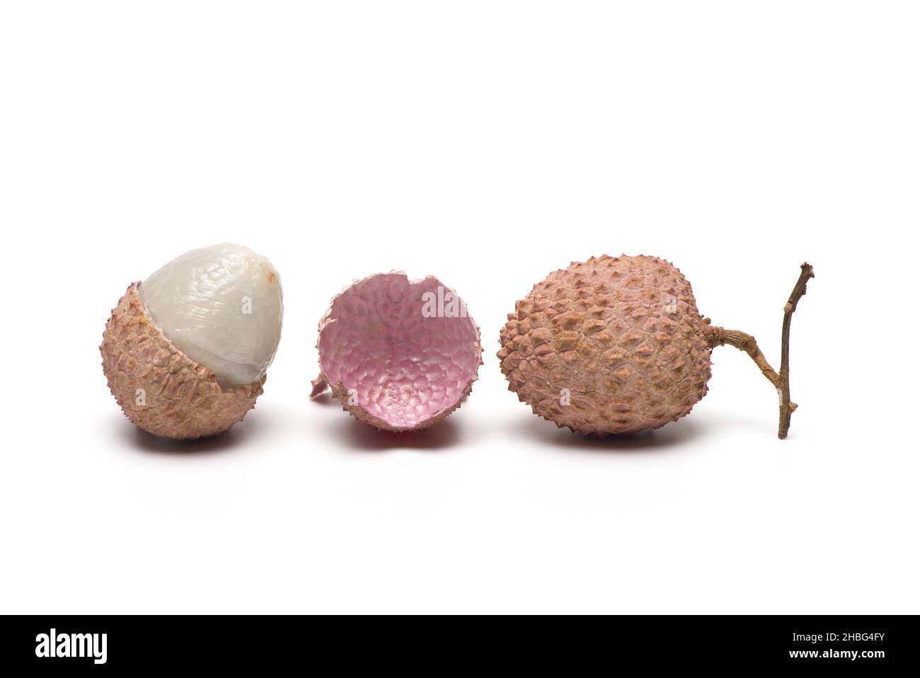 a ripe lychee next to an open cut lychee half showing the inside ...