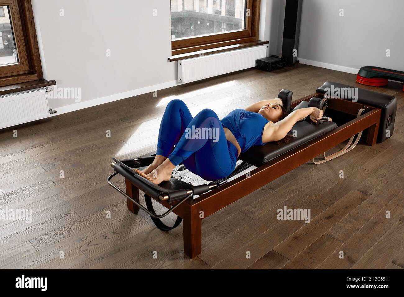 The instructor does exercises on the reformer, a beautiful girl trains ...