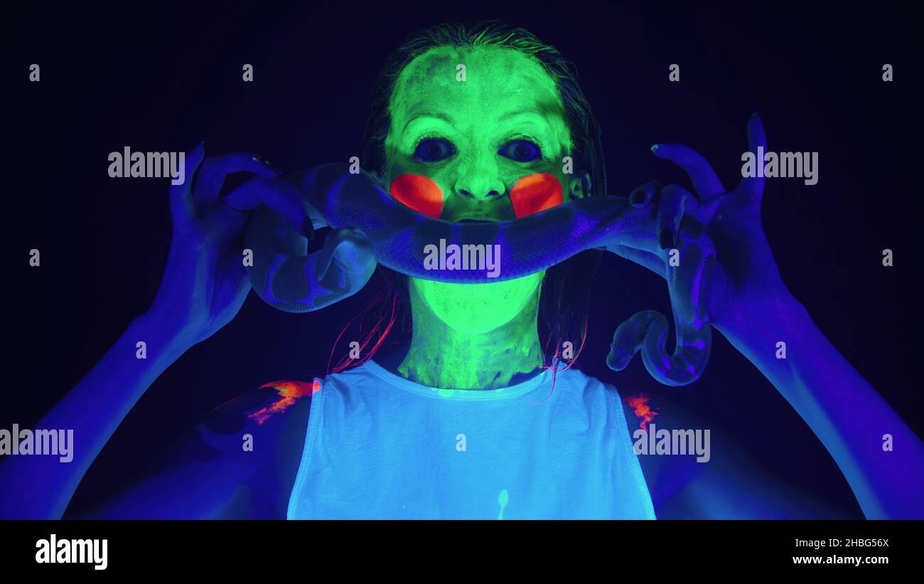 Photo of girl with scary painted face in ultraviolet light holding ...