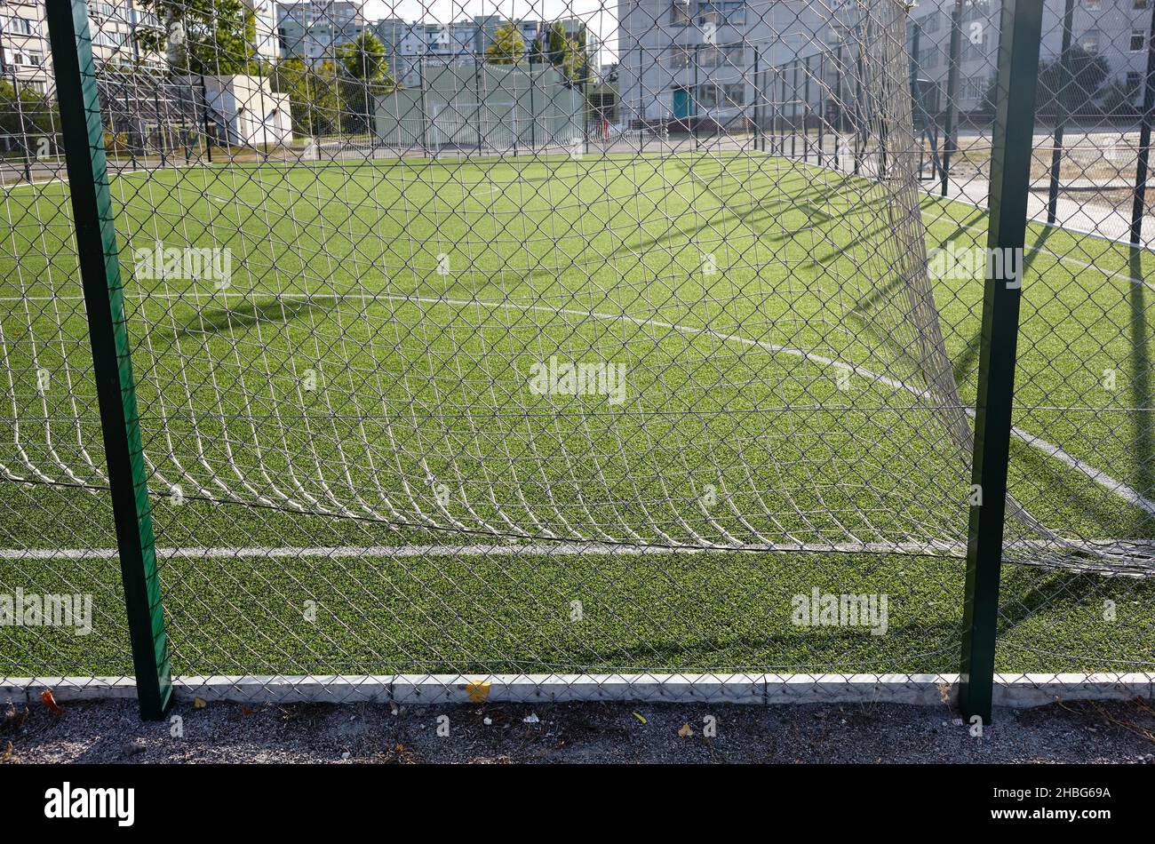 Lawn field for playing football behind the green fence mesh. Close-up ...