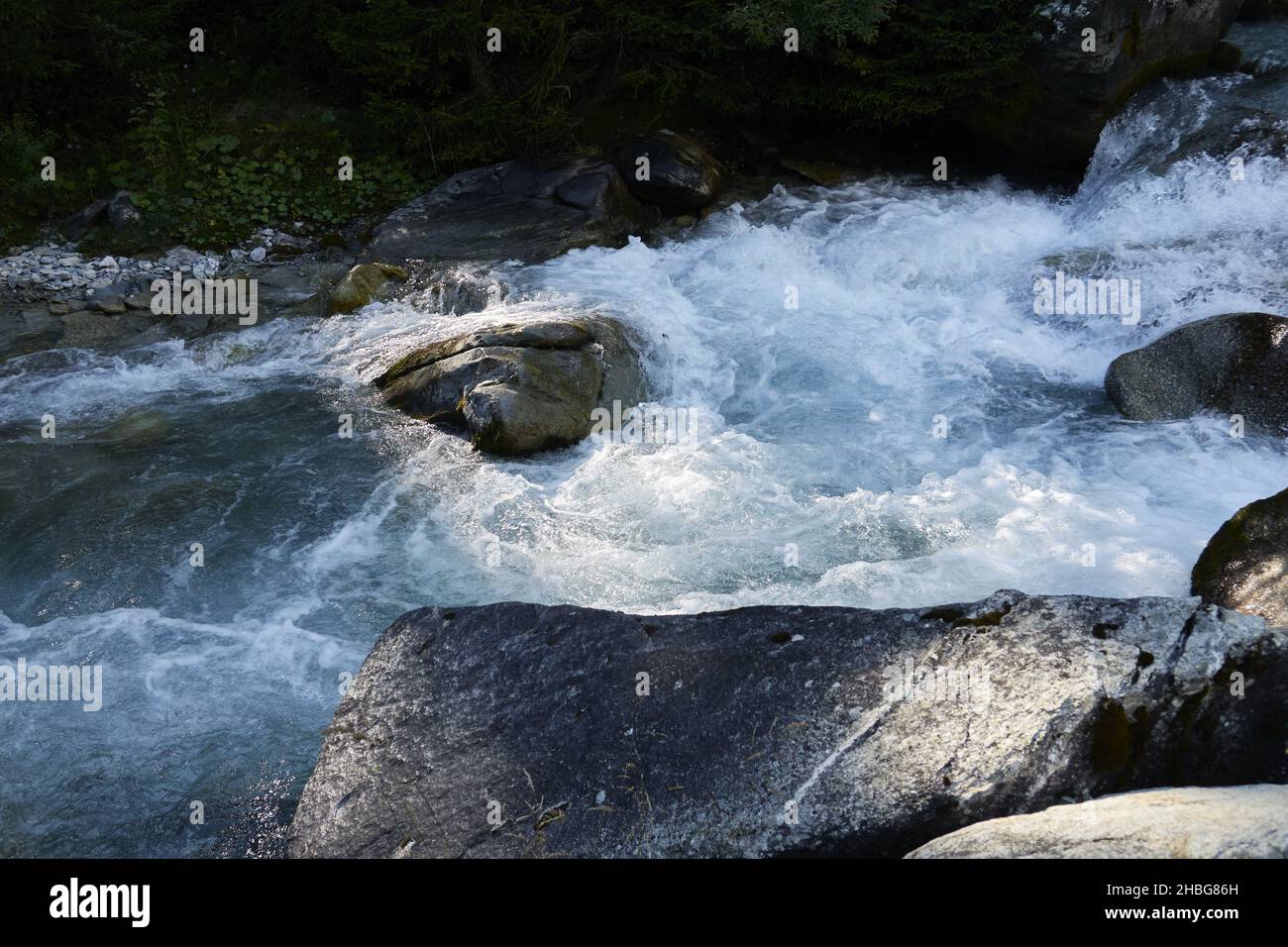 A river with a strong current and jagged rocks sticking out of the ...