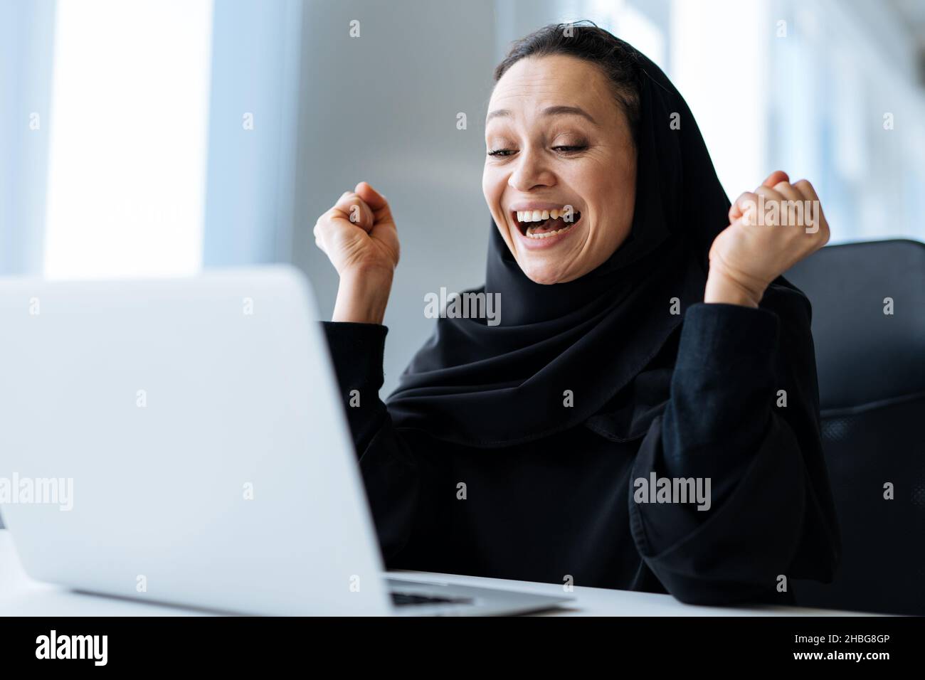 beautiful woman with abaya dress working on her computer. Middle aged ...