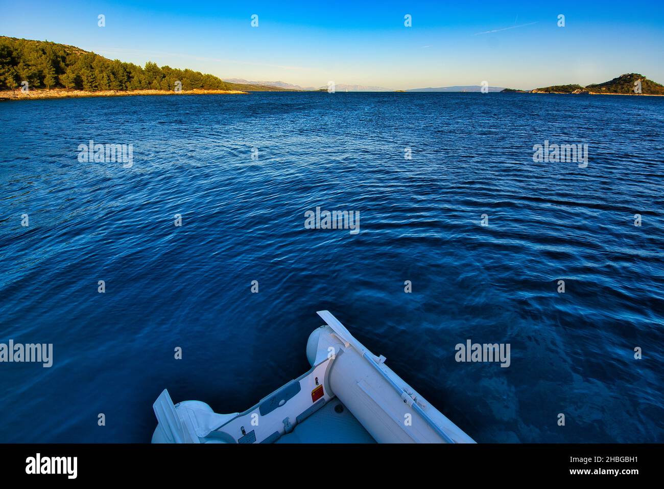 Small dinghy in a bay in Croatia at sunset with brilliant colors of sky ...