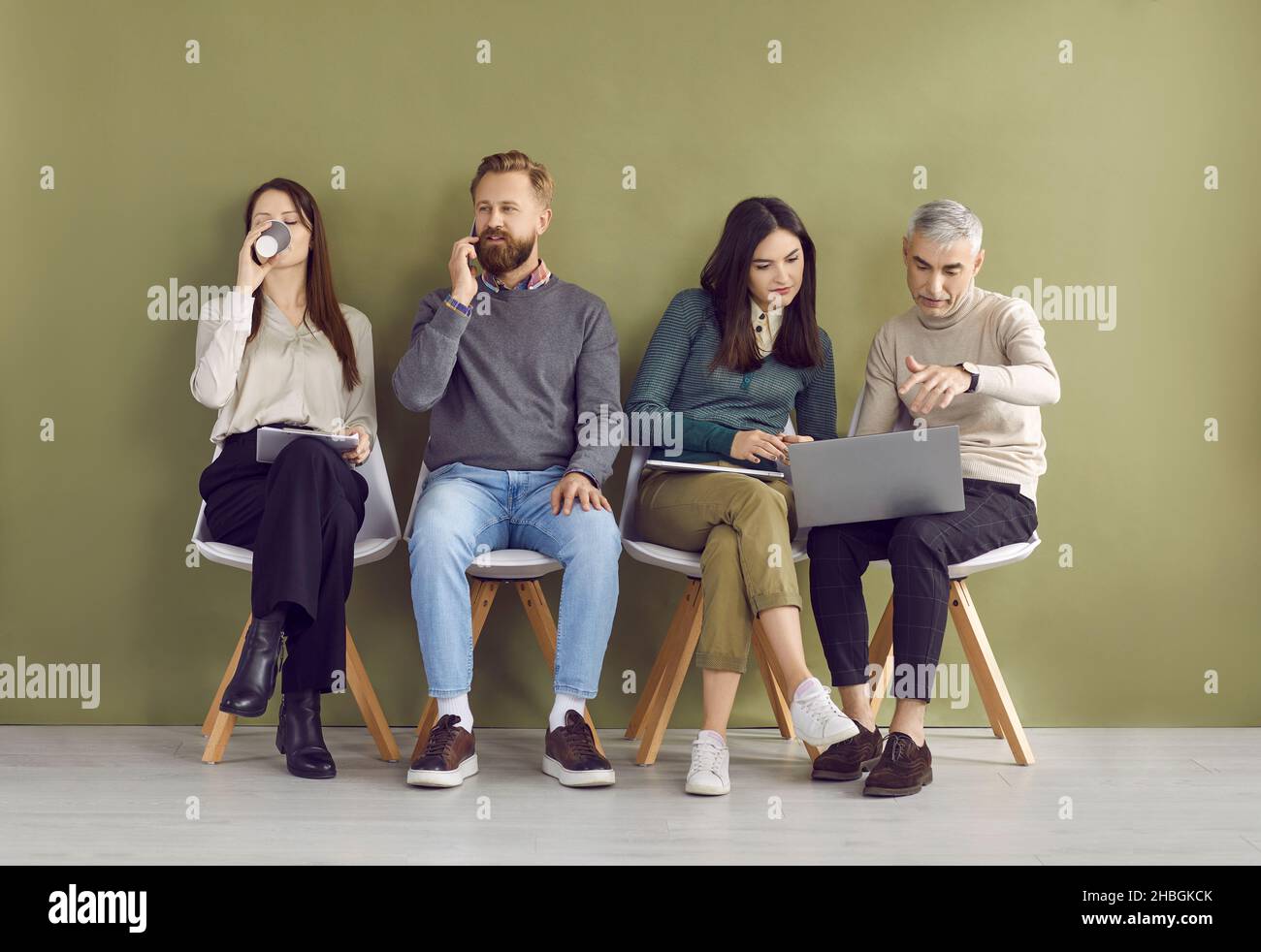 Group of people sitting in line by office wall waiting for meeting or ...