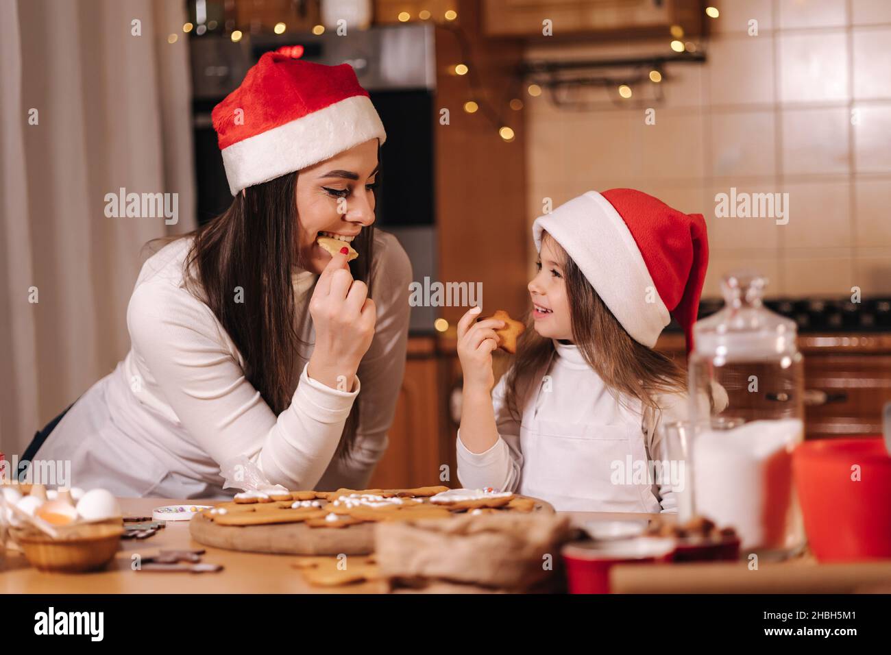 Adorable little girl and her mom in santa hat eating homemade ...