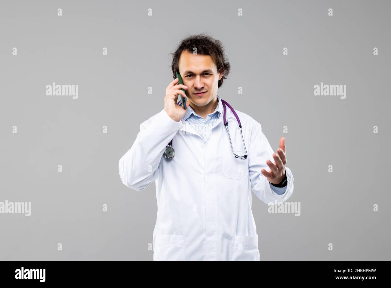 Portrait of a doctor making a phone call against a white background ...