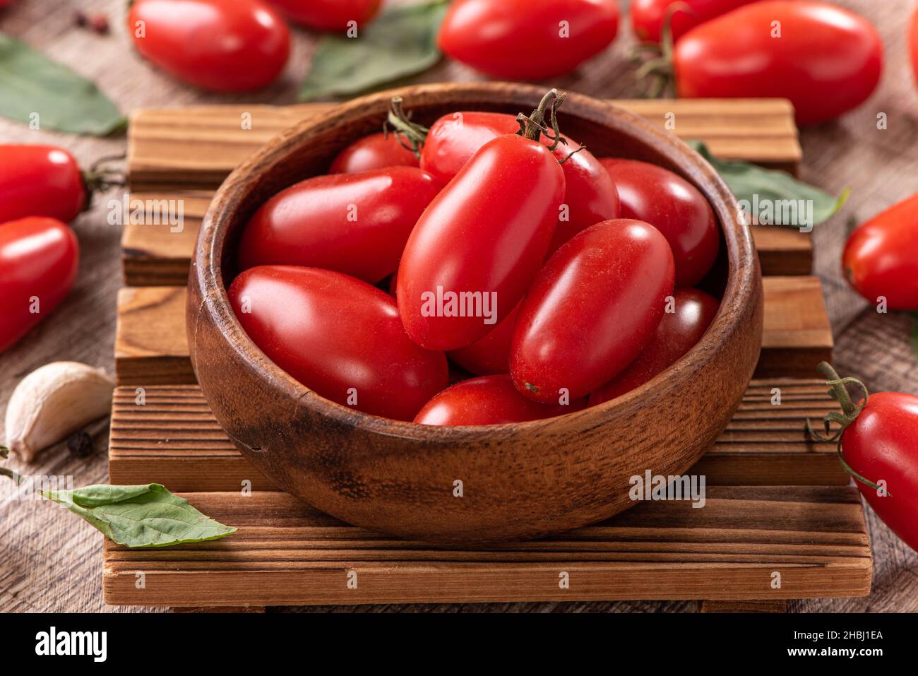 Close up of fresh cherry tomatoes in a basket with spices on wooden ...