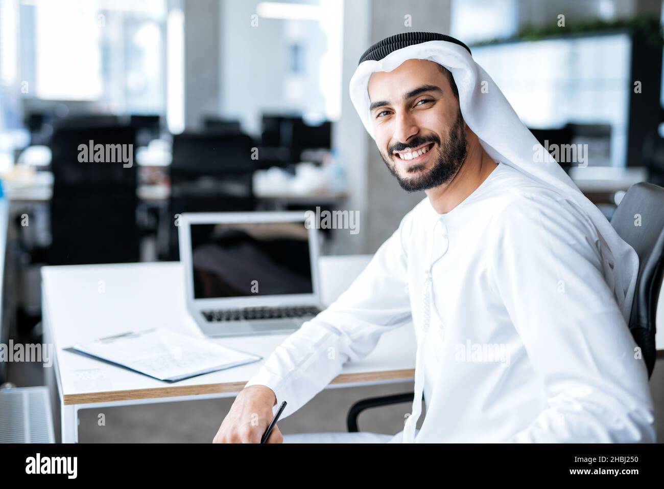 Handsome man with dish dasha working in his business office of Dubai ...