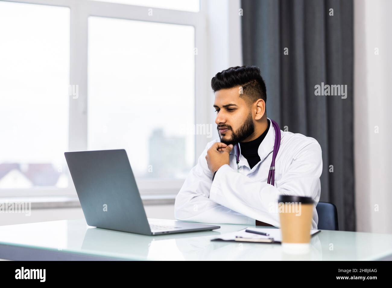 Doctor sitting at his desk with laptop computer Stock Photo - Alamy