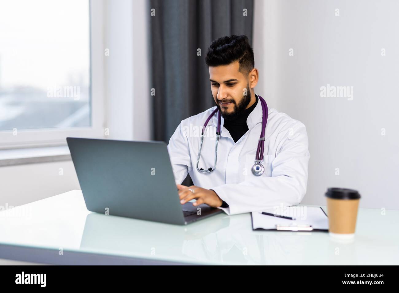 Doctor sitting at his desk with laptop computer Stock Photo - Alamy