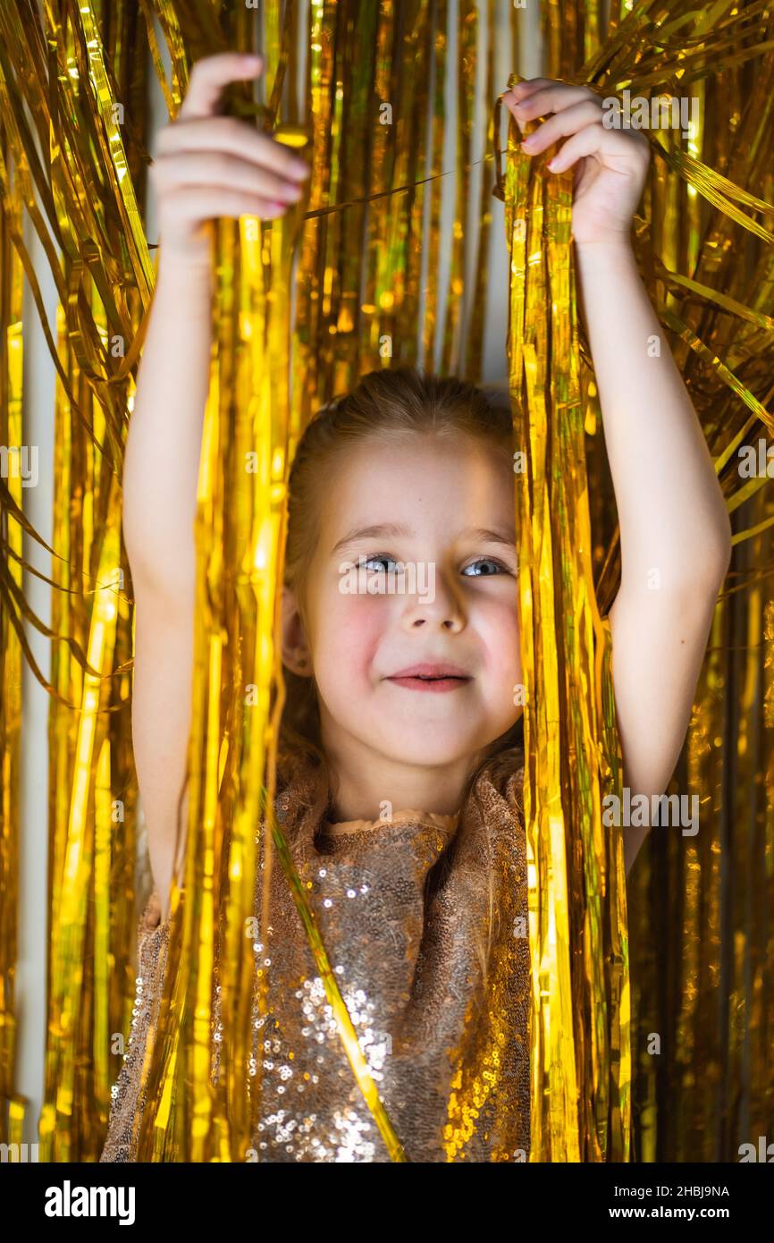 Cute blonde toddler girl wearing fancy dress smiling against golden glitter background Stock ...
