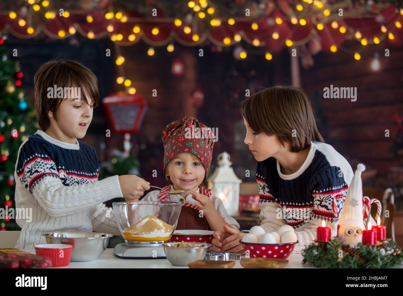 Cute blond child and his brothers, baking christmas cookies at home ...