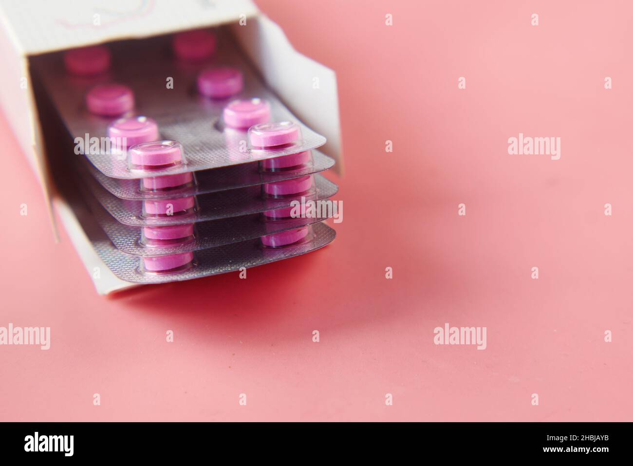 Close up of pills of blister pack in a paper packet on pink background ...