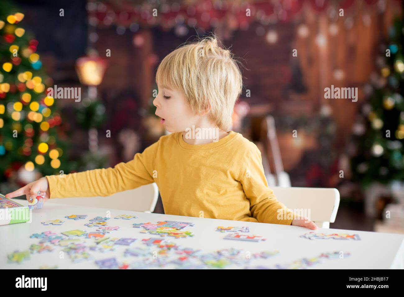 Blond child, toddler boy, having fun at home on Christmas, assembling ...