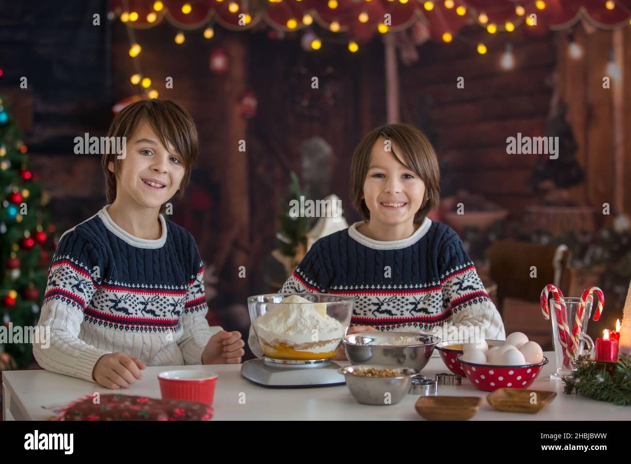 Cute blond child and his brothers, baking christmas cookies at home ...