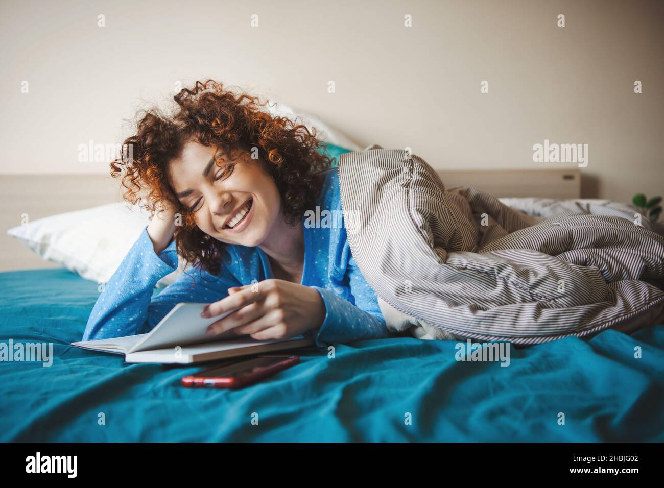 Caucasian woman reading something during leisure time in bedroom ...