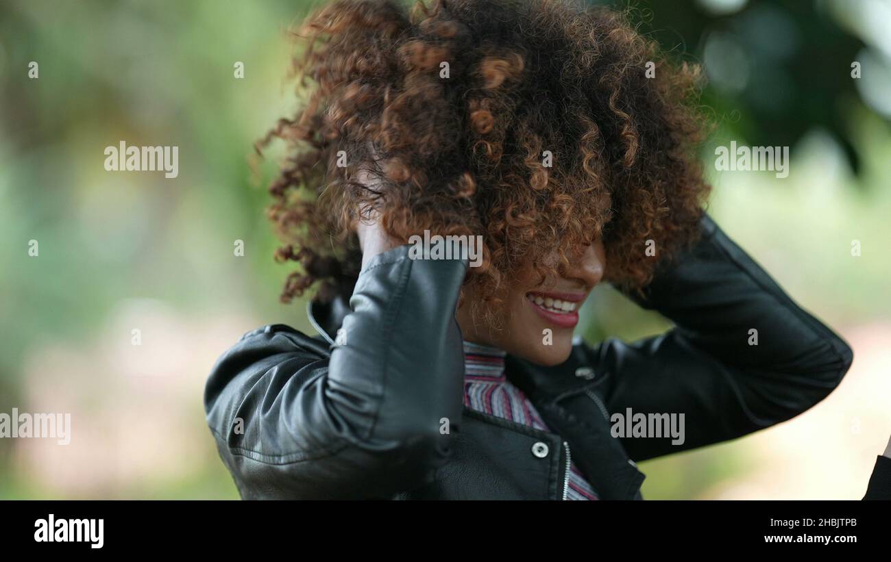 Black woman adjusting curly hair outside Stock Photo - Alamy