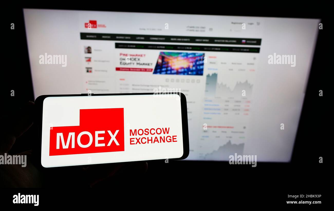 Person holding mobile phone with logo of Russian stock market company ...