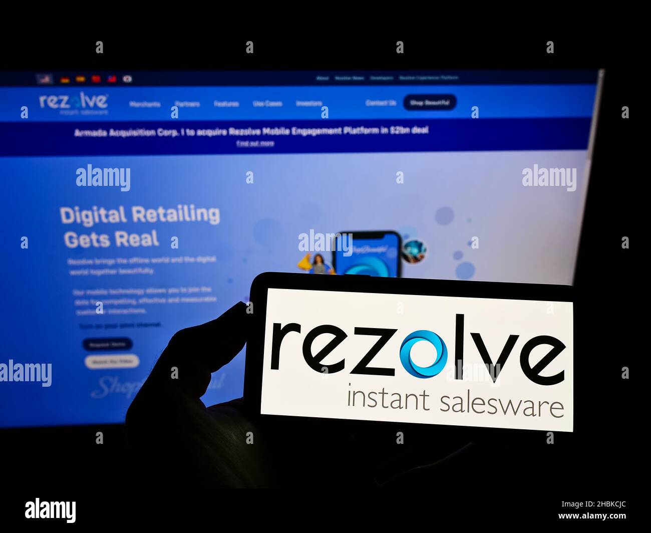 Person holding smartphone with logo of British mobile commerce company Rezolve Limited on screen ...