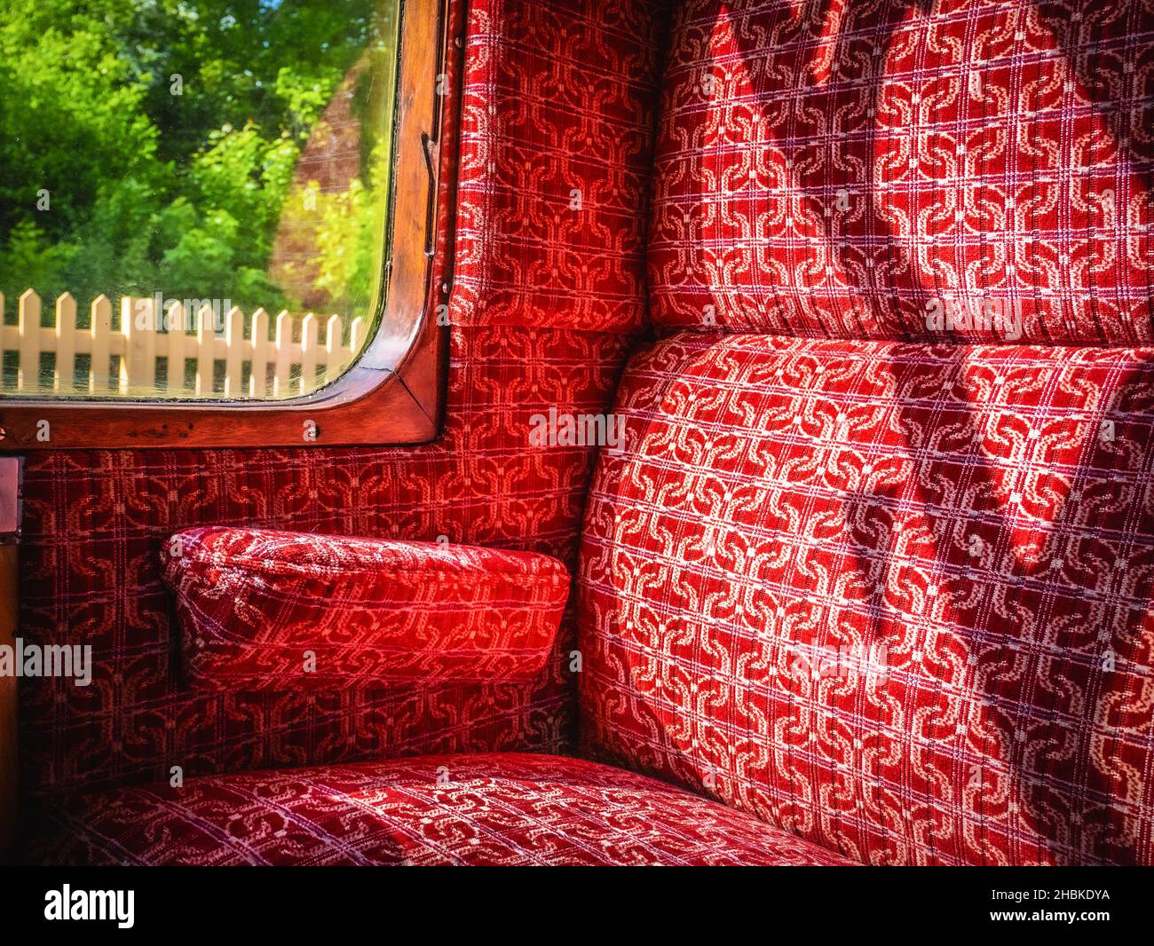 Vibrant red classic train seating cast in shadow and light from a ...