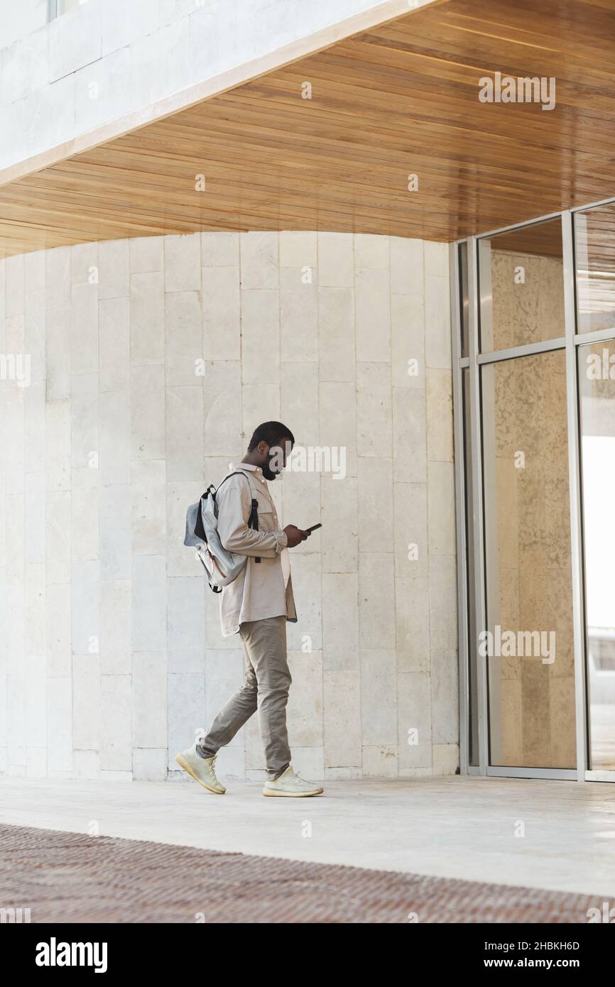Minimal full length shot of black young man walking into office ...