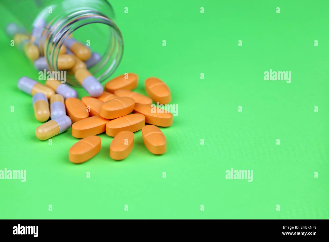 Pills on green background, bottle of different medication in capsules ...