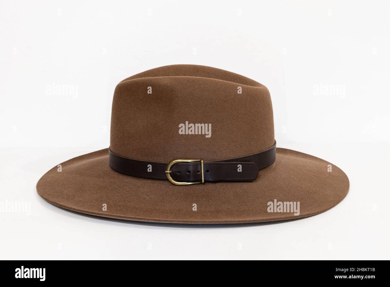 Classic cowboy brown felt hat with strap and copper closure on white ...