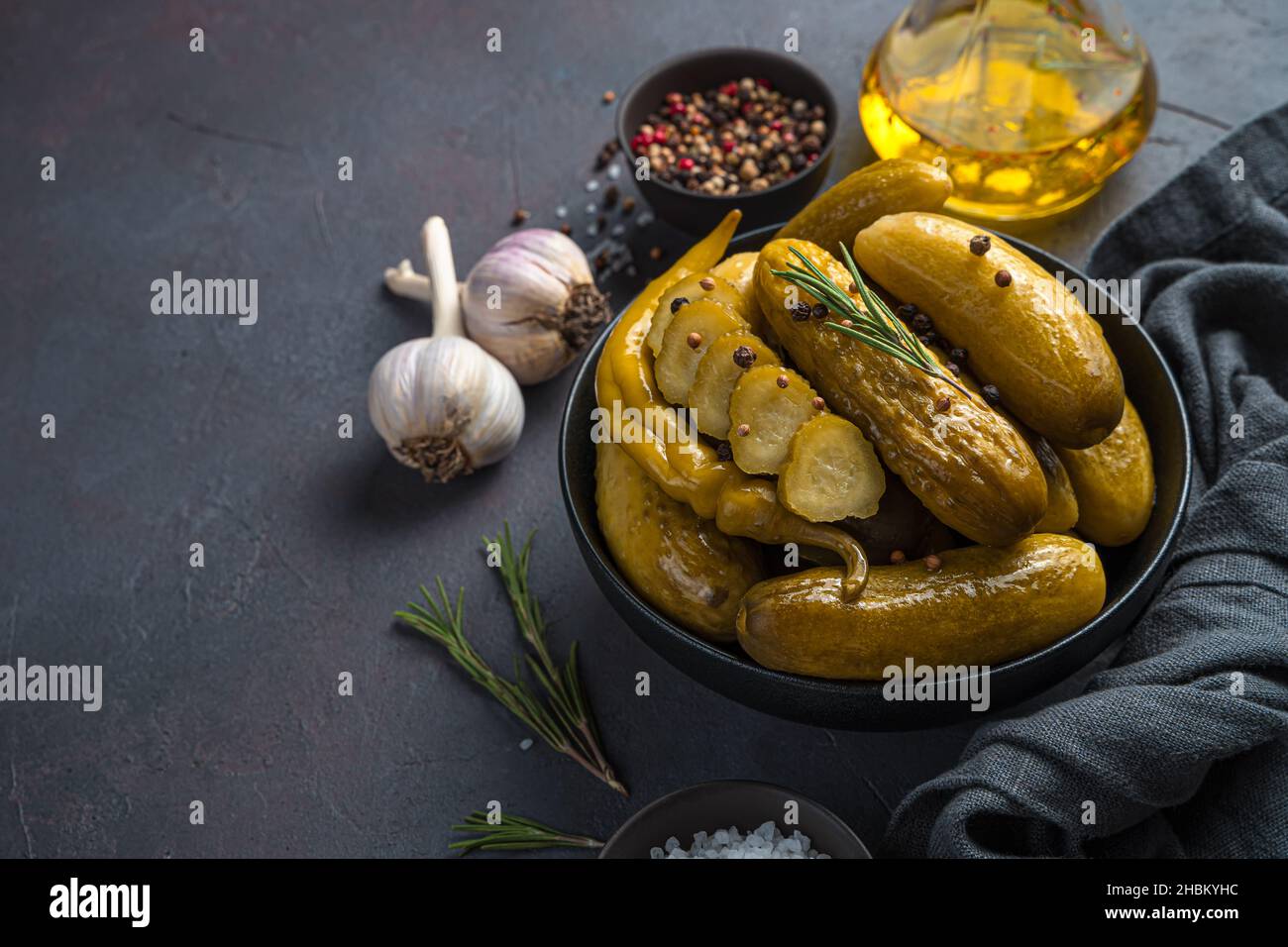 pickled cucumbers with garlic, butter and rosemary on a dark background ...