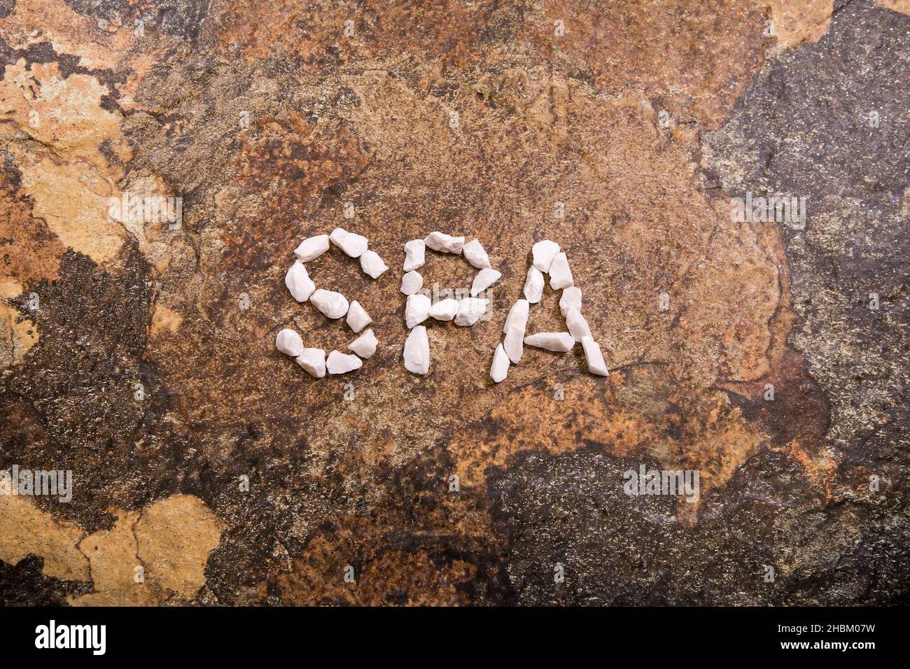 A top view of the word "Spa" with white stones over a brown stone ...