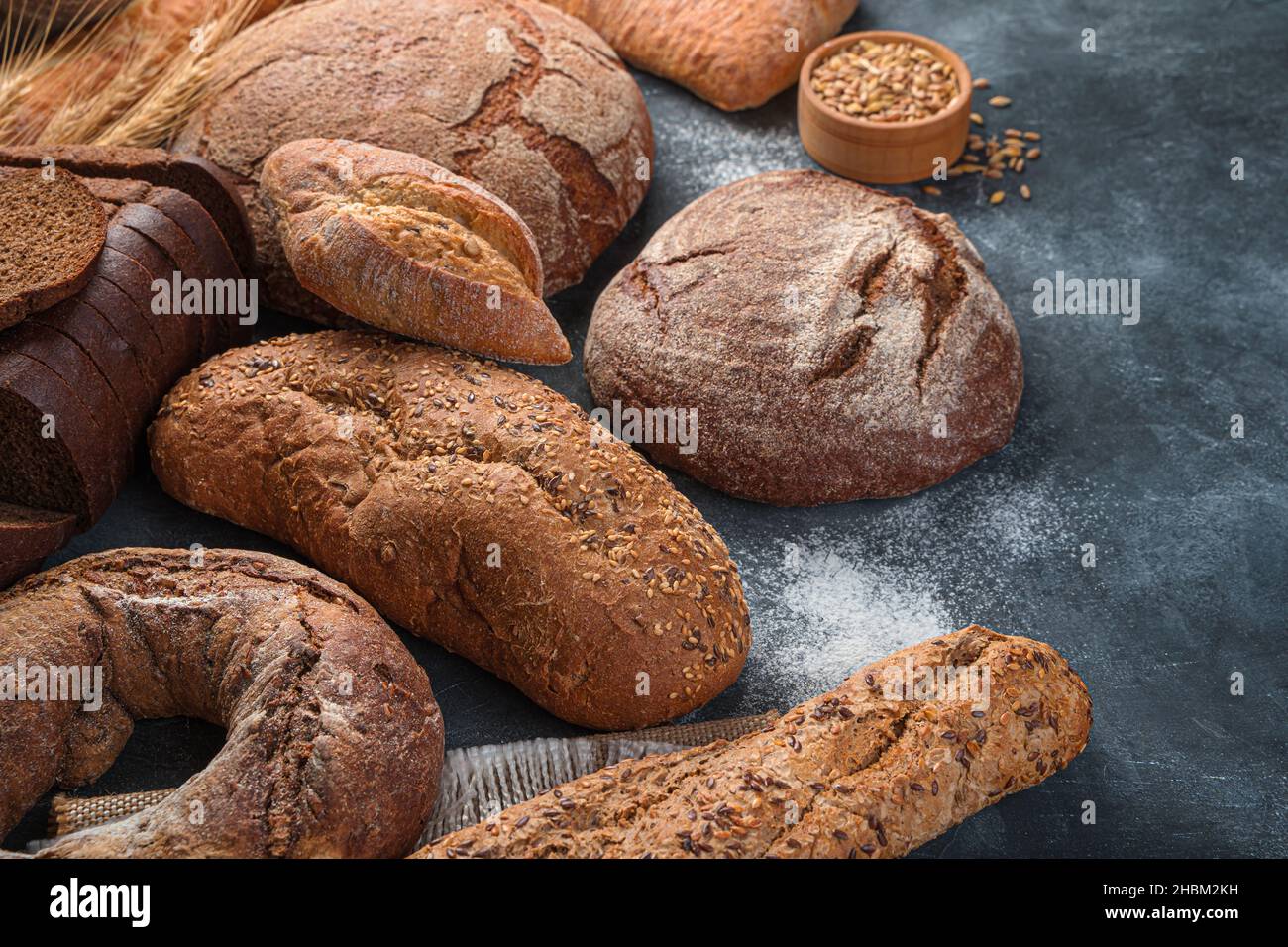 Assortment of rye and wheat bread on a dark background with flour. Side ...