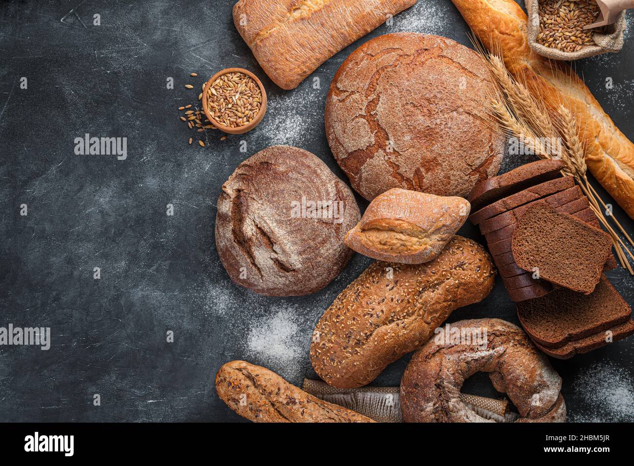 Rye and wheat bread of different types on a dark background with flour ...