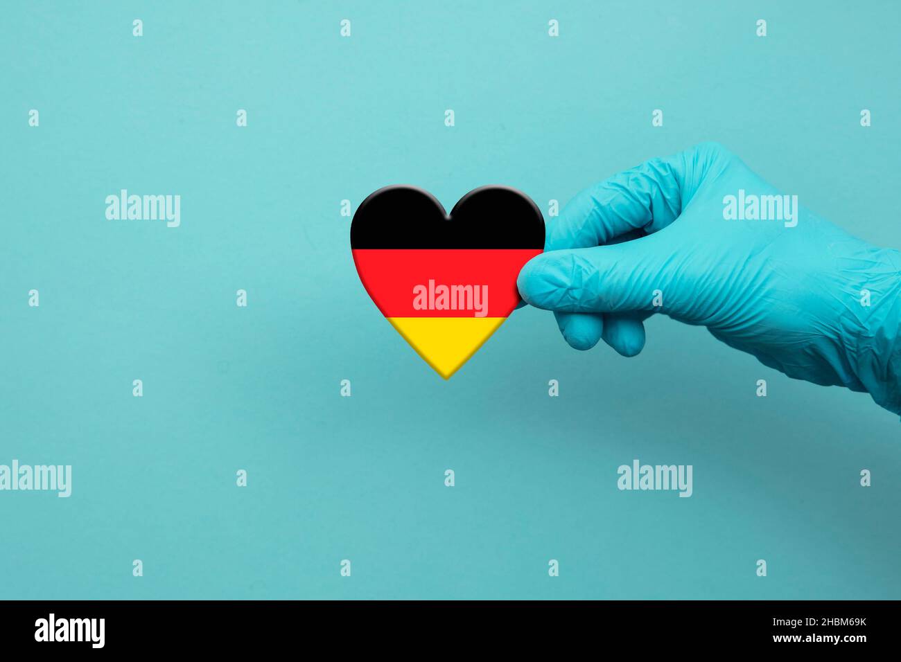 Medical workers hand wearing surgical glove holding Germany flag heart ...