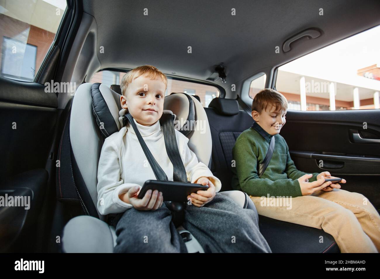 Portrait of cute little boy sitting in car seat in family car ready for ...