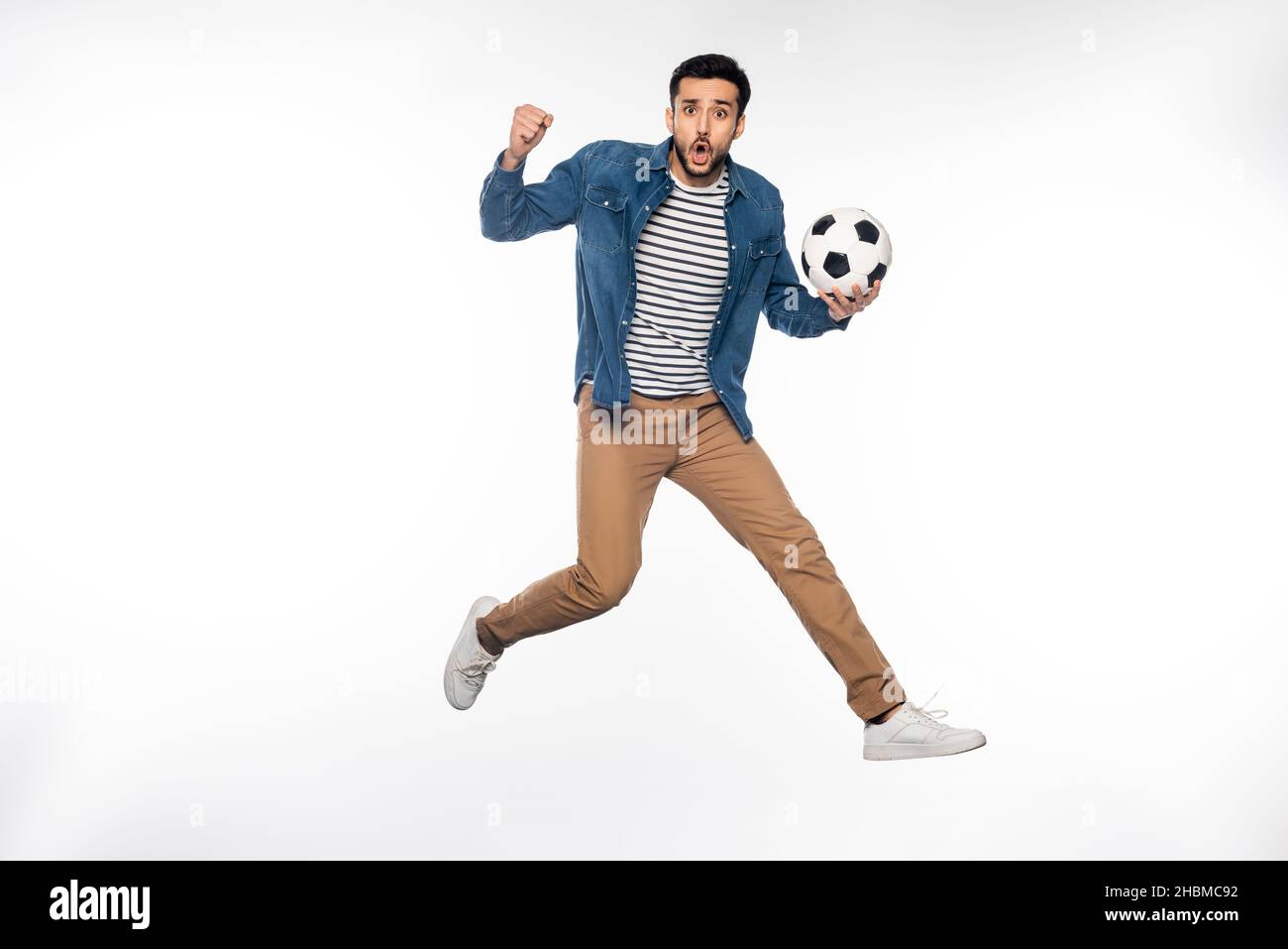 worried man levitating while holding soccer ball and cheering on white ...