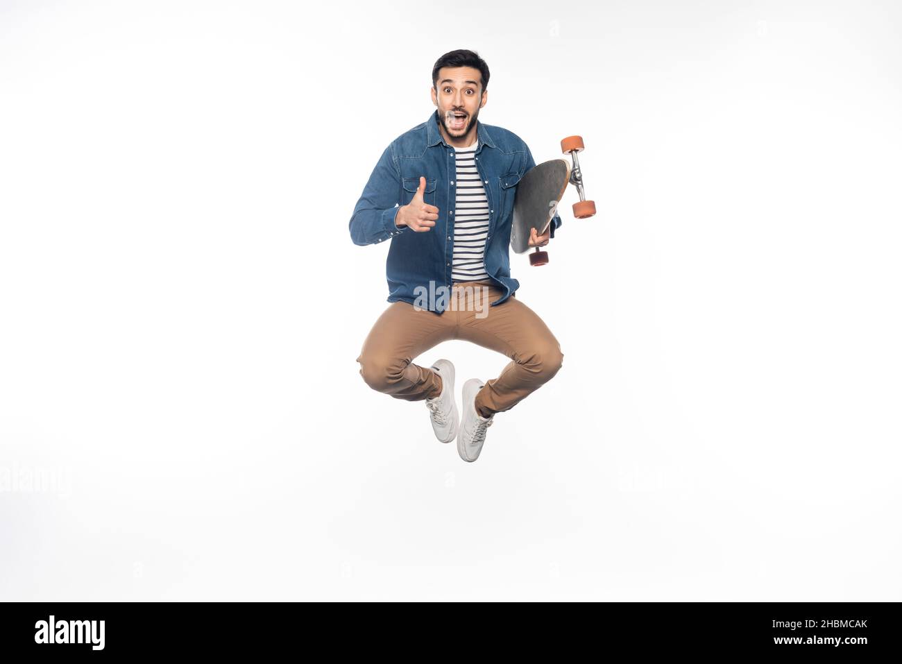 happy man levitating while holding longboard and showing thumb up on ...