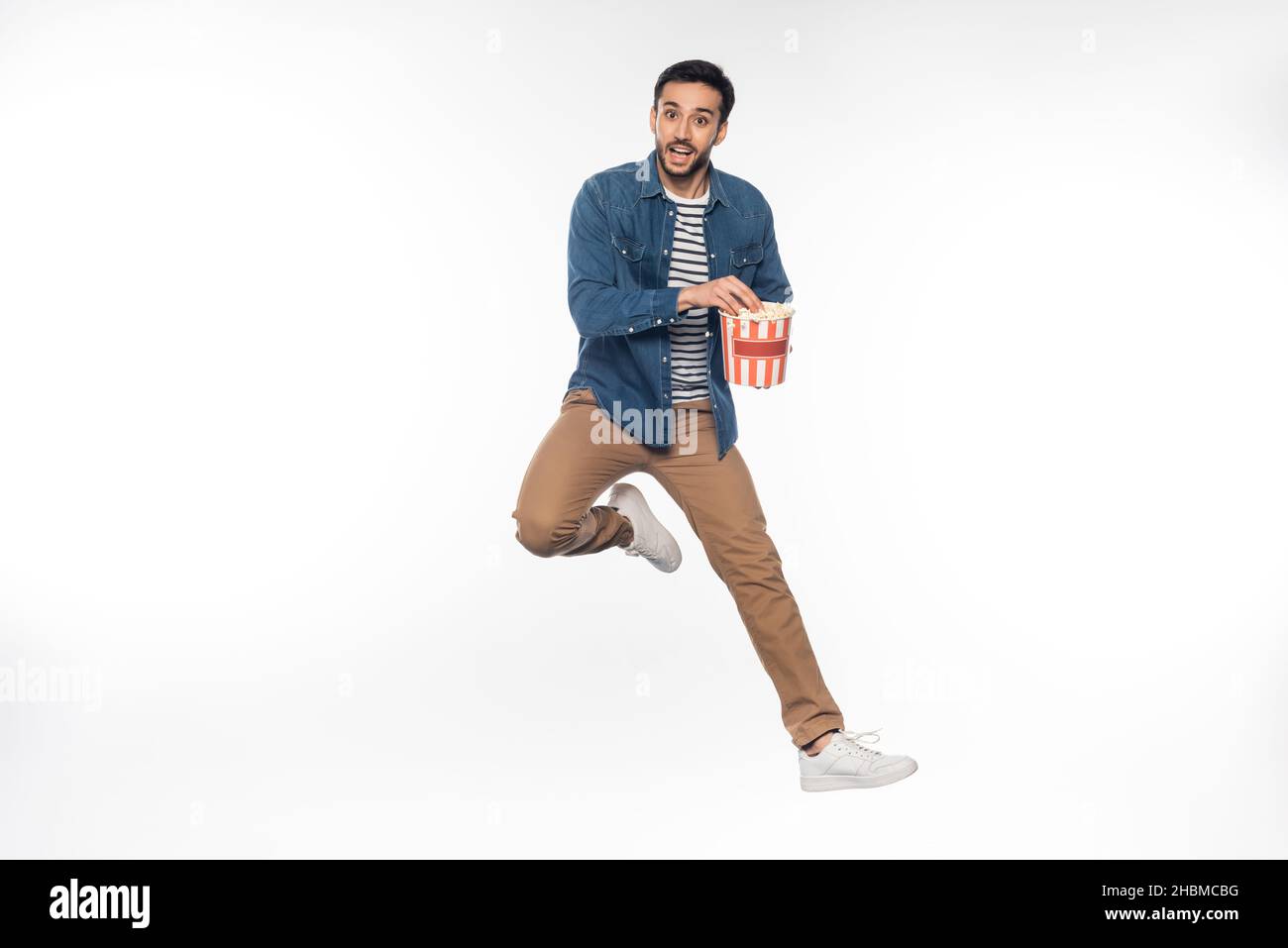 happy man levitating while holding popcorn bucket on white Stock Photo ...