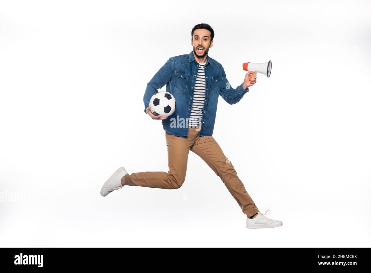 happy man levitating while holding soccer ball and loudspeaker on white ...
